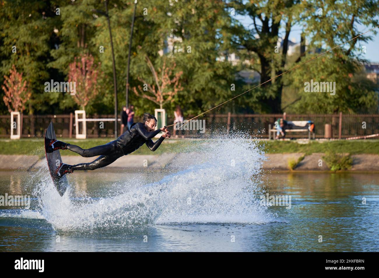 Wakeboarder making tricks while wakeboarding on lake. Young man surfer ...