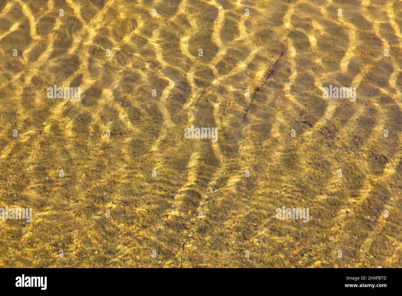 Shallow water over rock bottom with reflections and small rippling ...