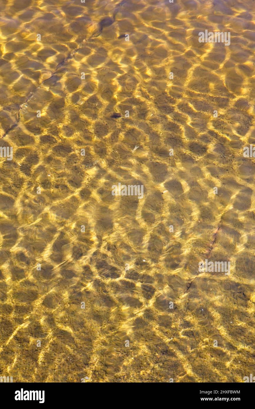 Shallow water over rock bottom with reflections and small rippling ...