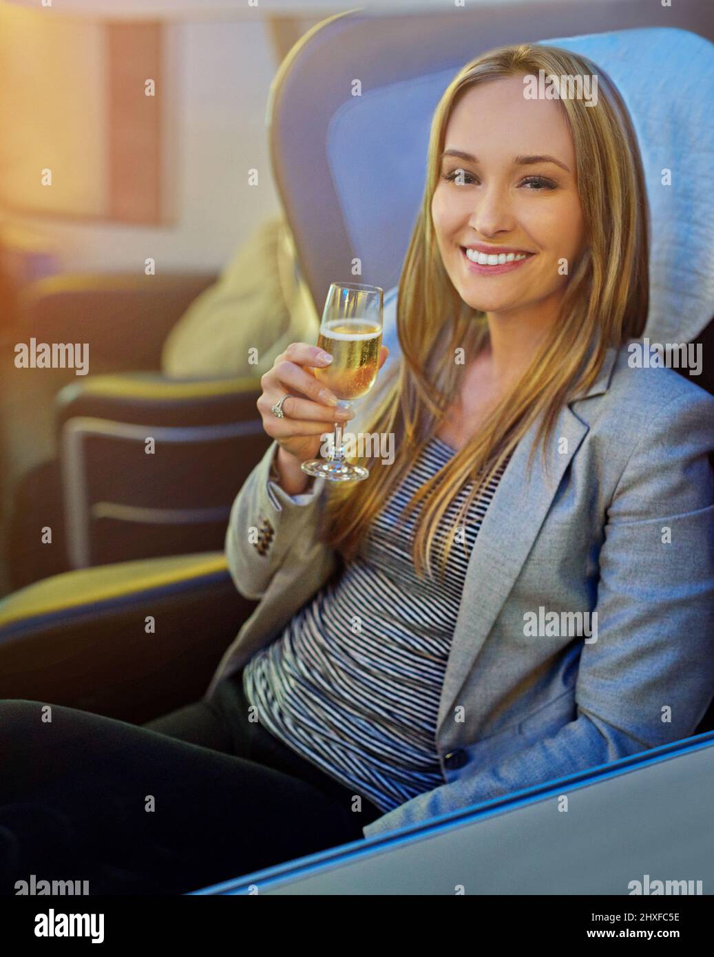 Flying in style. Portrait of a young woman drinking champagne in first ...