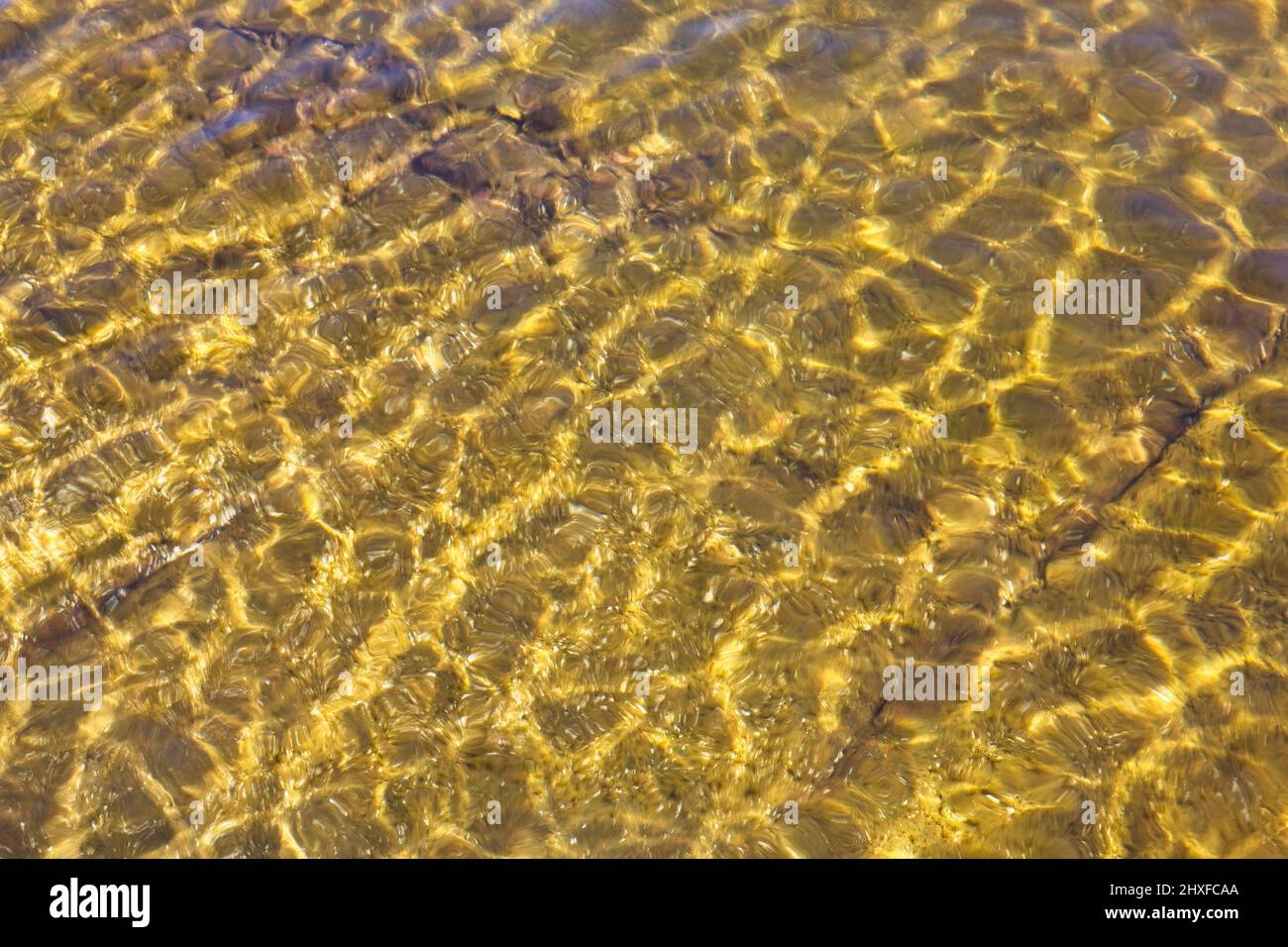 Shallow water over rock bottom with reflections and small rippling ...