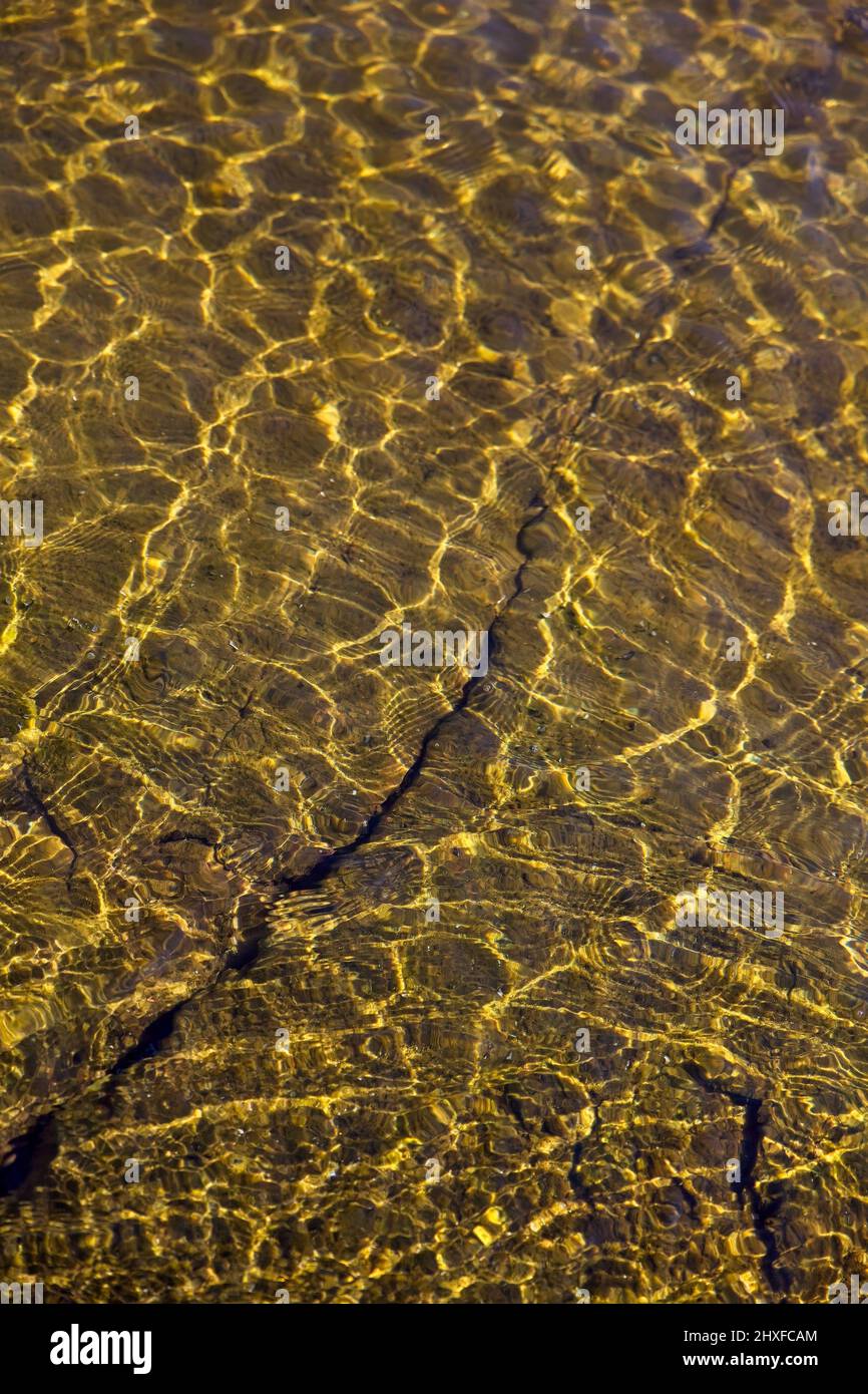 Shallow water over rock bottom with reflections and small rippling ...