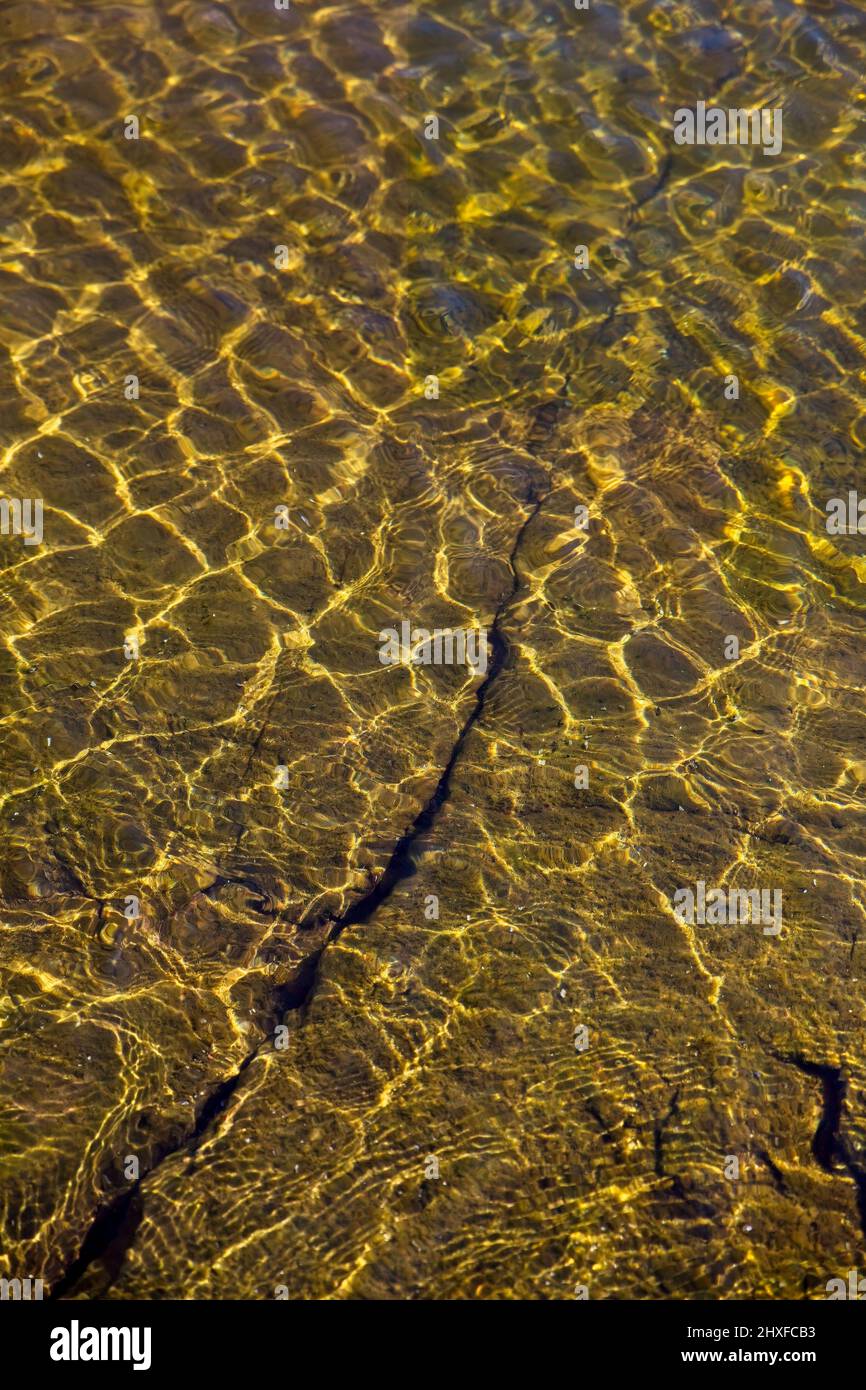 Shallow water over rock bottom with reflections and small rippling ...