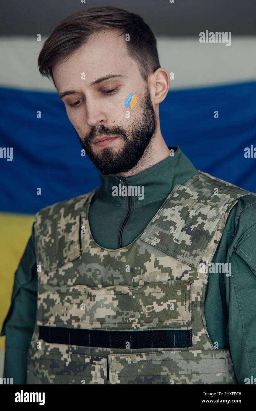 Portrait of young angry man in body armor with ukrainian flag on his ...