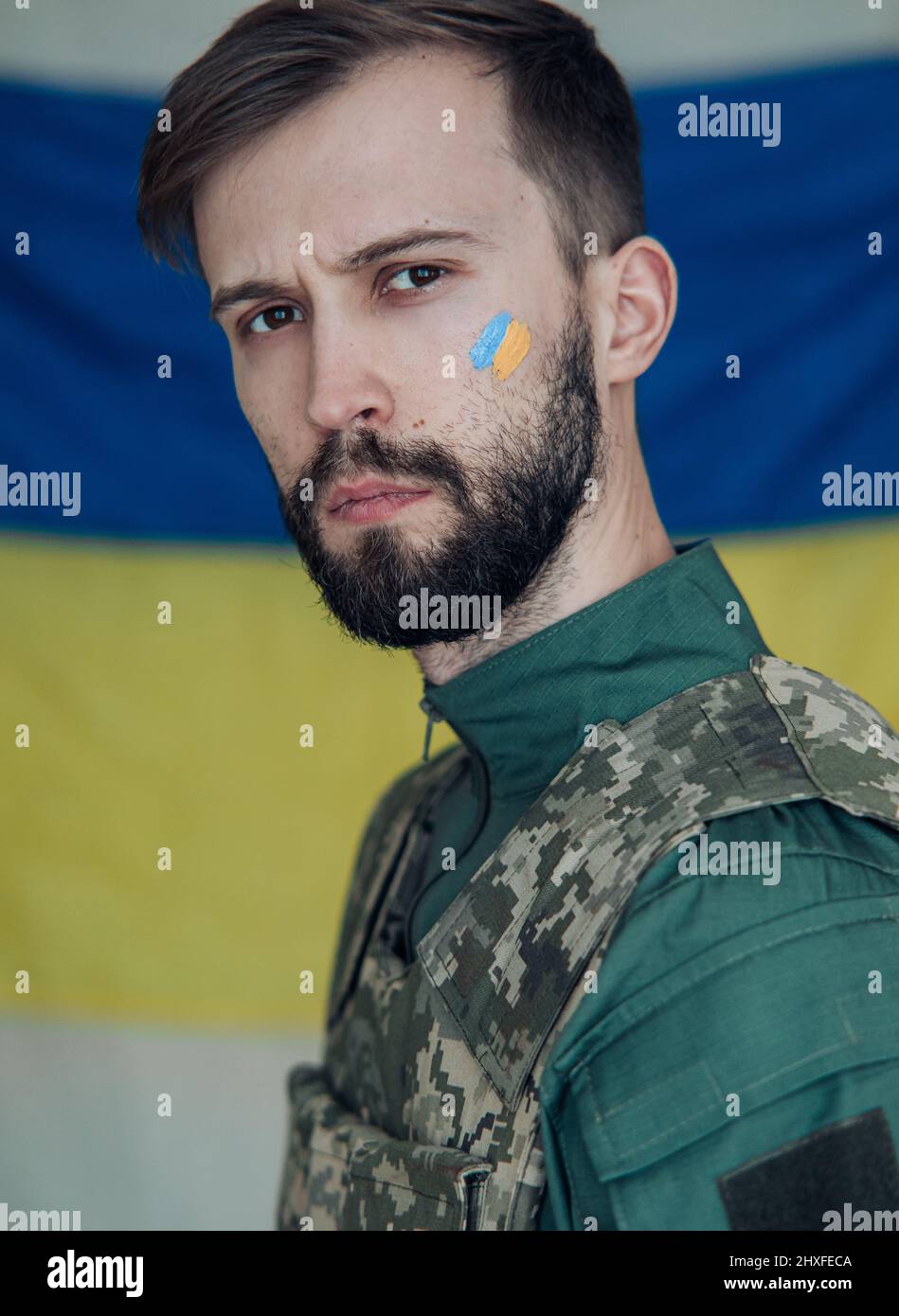 Portrait of young angry man in body armor with ukrainian flag on his ...