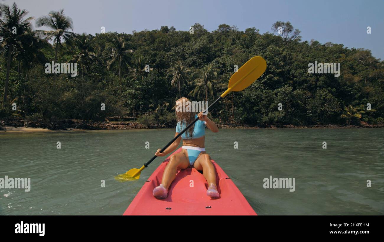 Attractive sportive blonde woman with sunglasses rows pink plastic ...