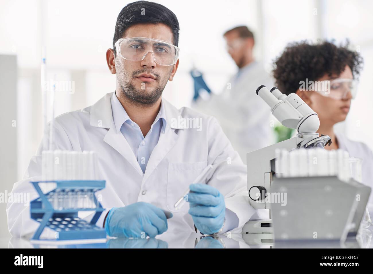 young scientist with a laboratory tube sitting at his desk Stock Photo ...