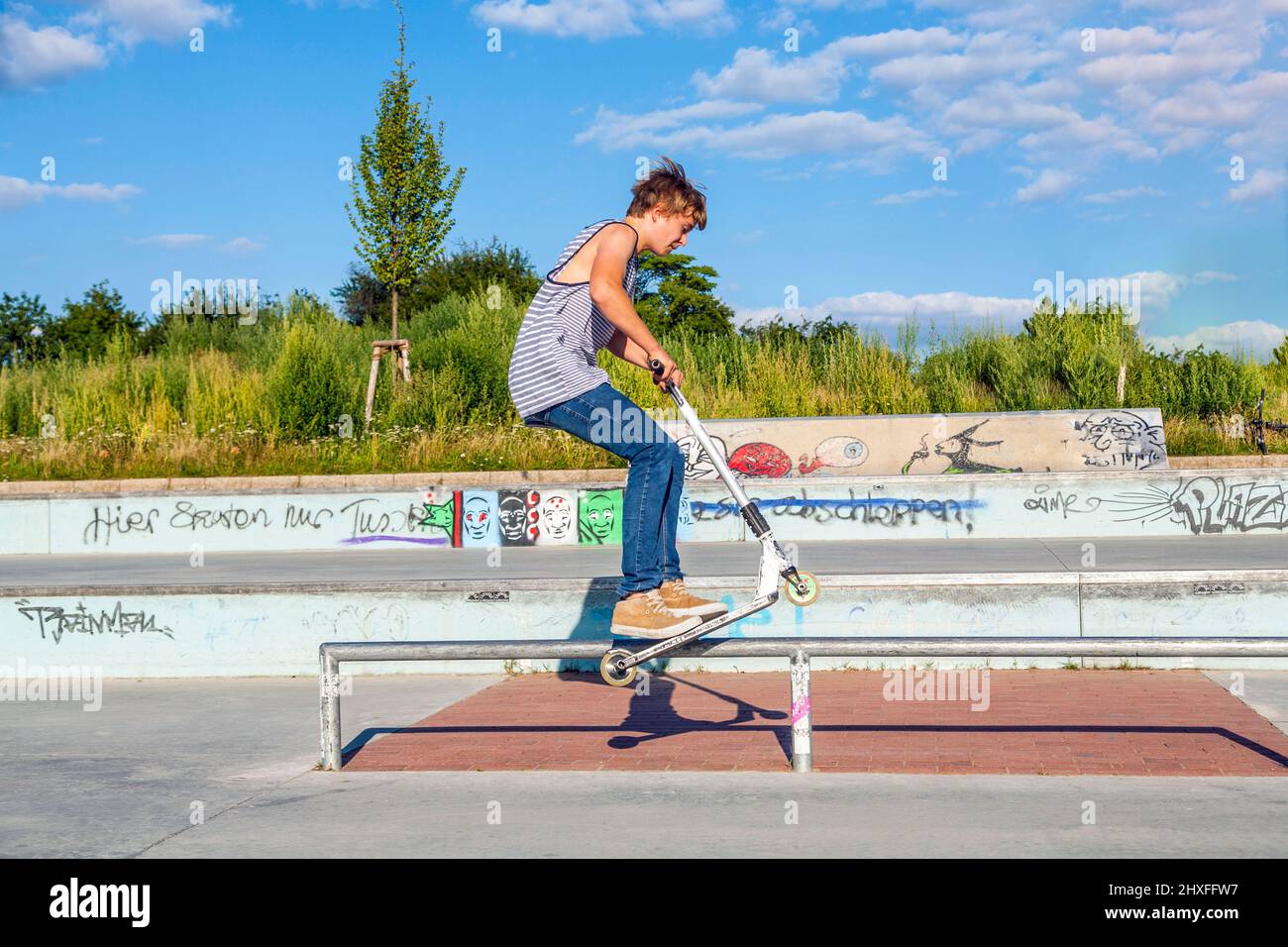 boy has fun jumping with his scooter at the skate park Stock Photo - Alamy