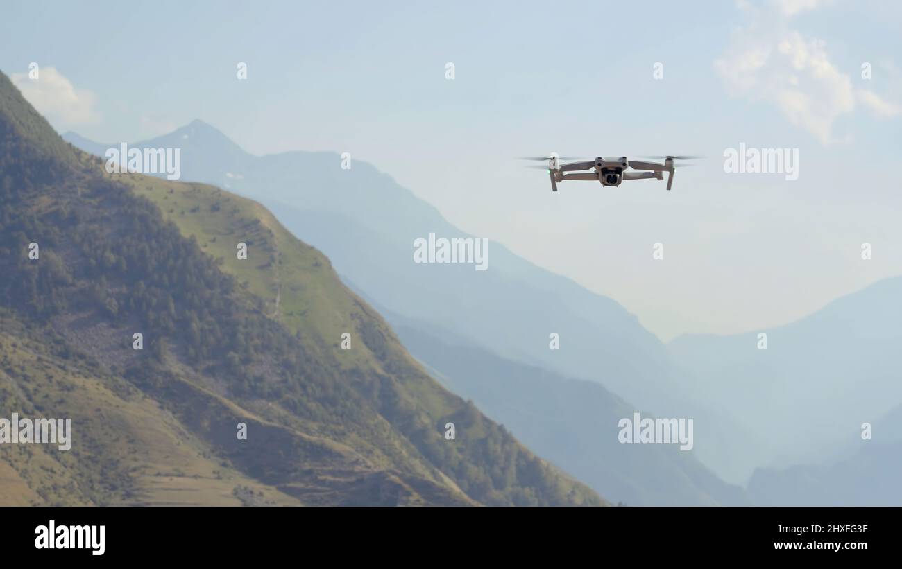 Aerial view of a quadcopter flying above green mountains on morning ...