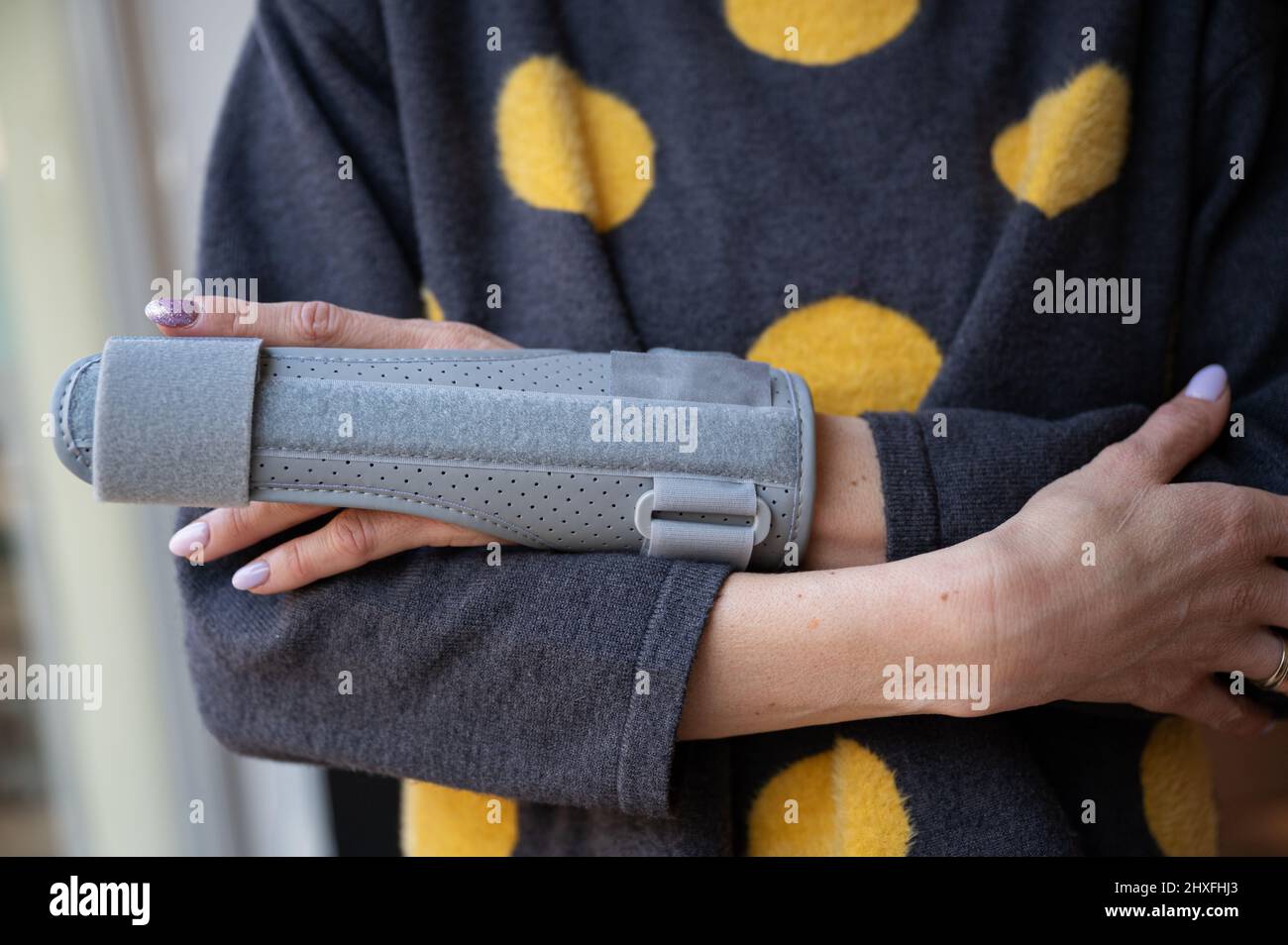 Closeup view of a woman cradling her injured arm with a brace on her ...
