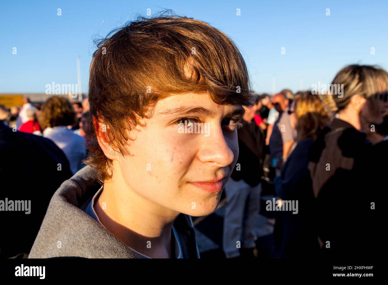 cute boy waiting with other people at the harbor to enter the ferry ...
