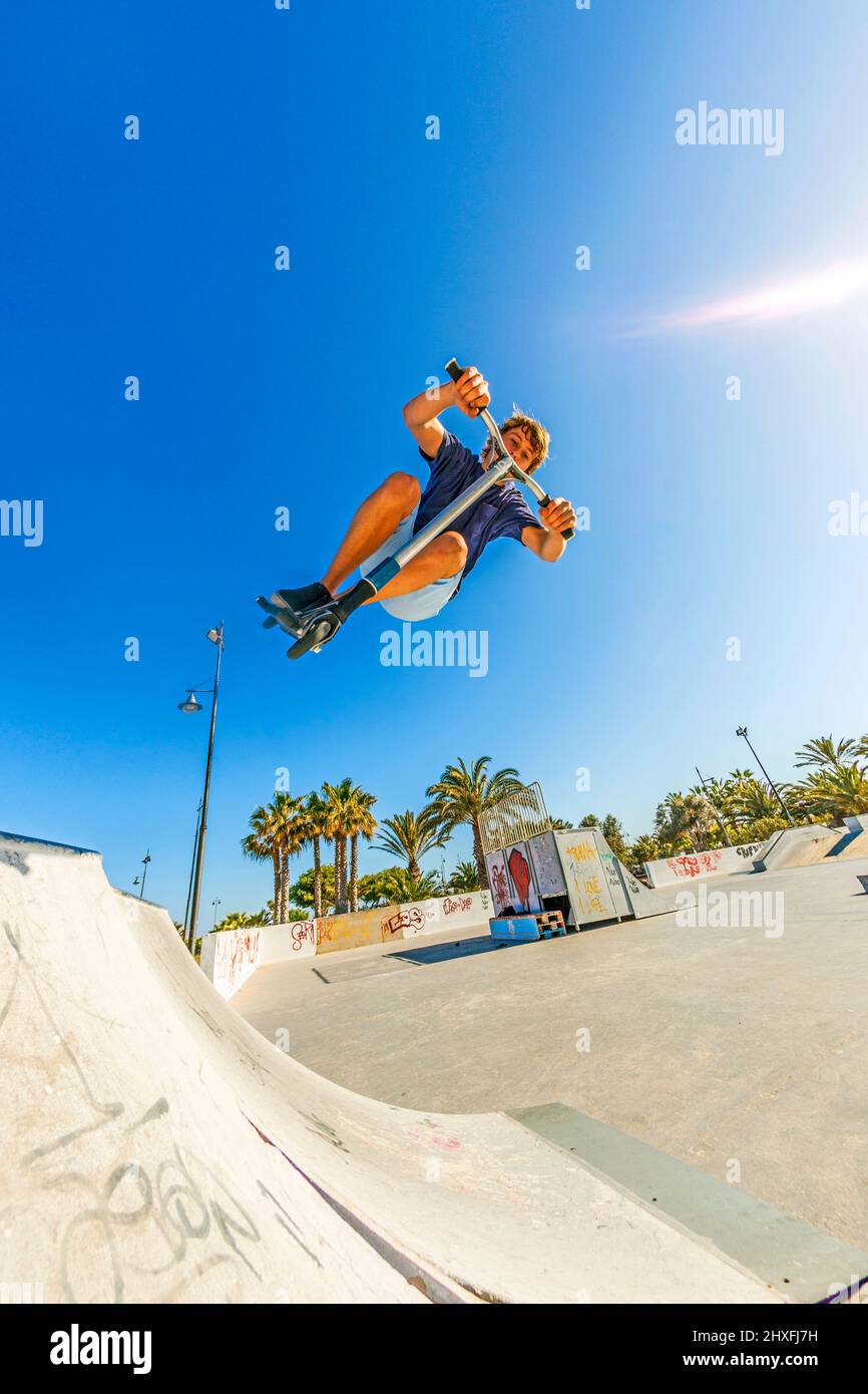 boy jumps with his scooter over a ramp Stock Photo - Alamy