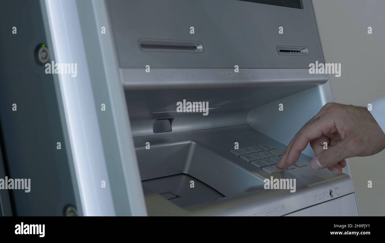 Male hand entering pin code on ATM keyboard, withdrawing money from ...