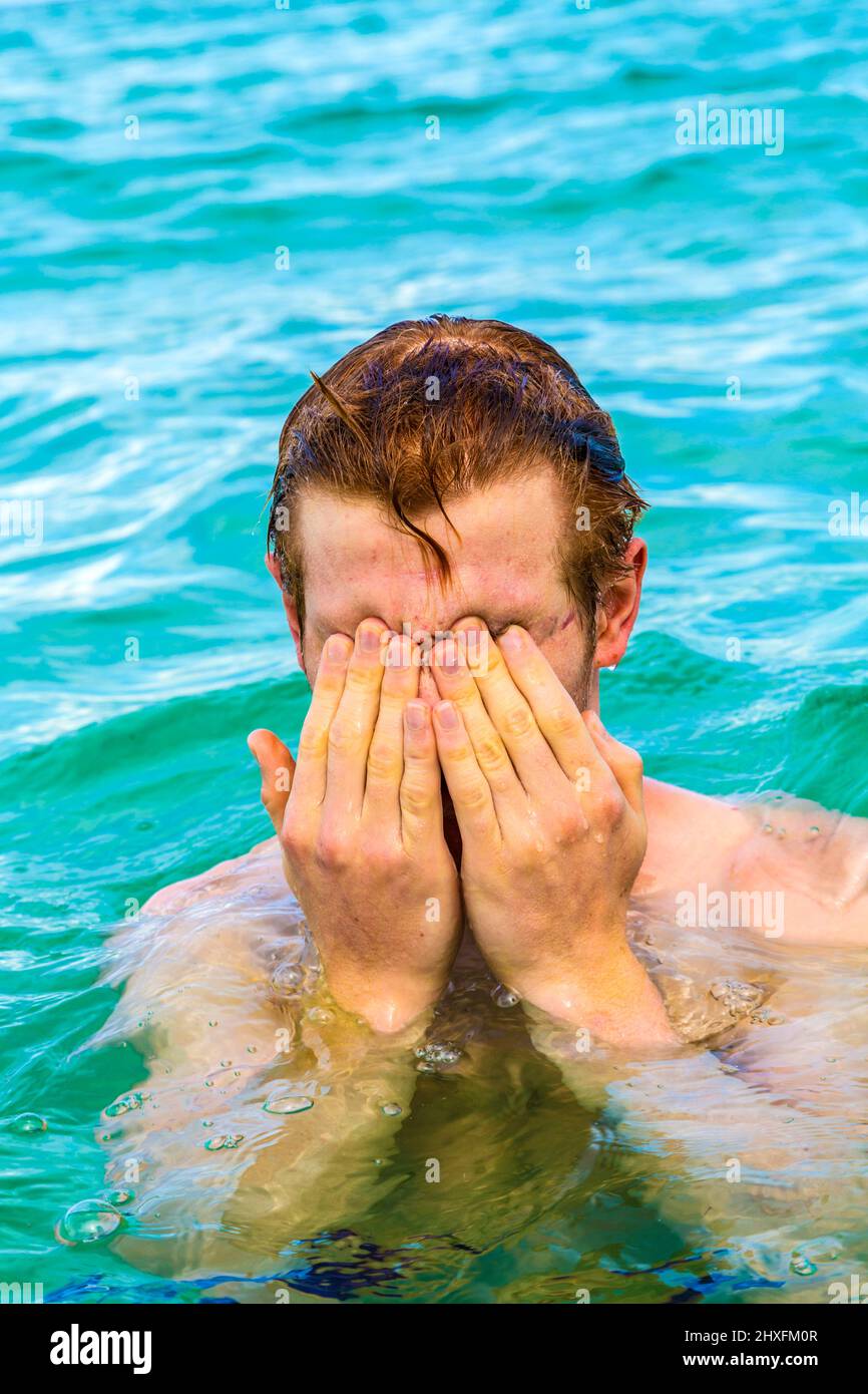 teenage boy cleans eyes of saltwater in the ocean Stock Photo - Alamy