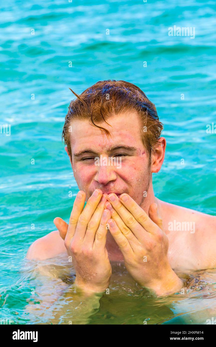 teenage boy cleans eyes of saltwater in the ocean Stock Photo - Alamy