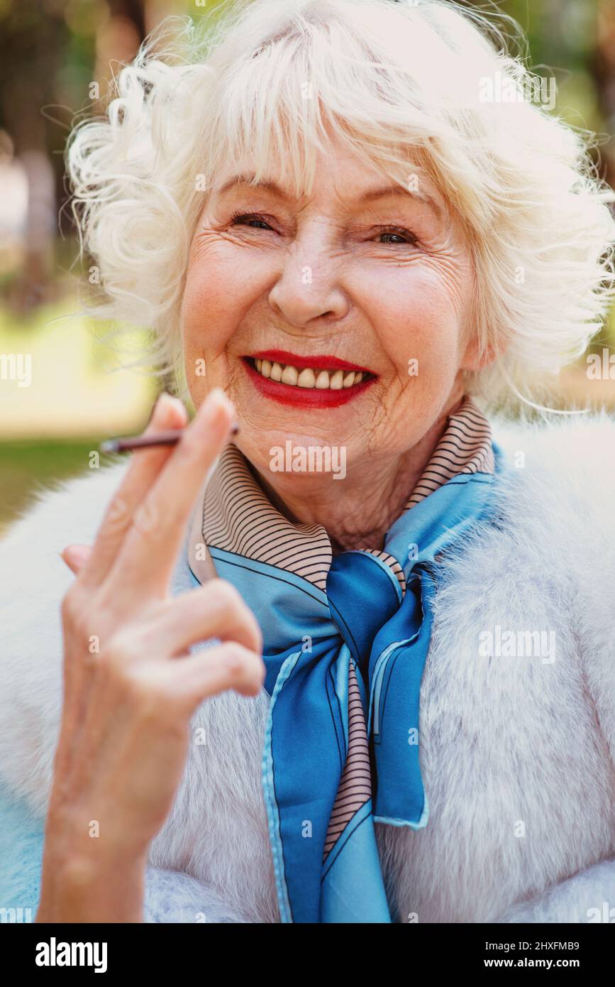 Smiling Senior Elegant Stylish Fashionable Woman With Grey Hair In Fur Coat Outdoor Smoking