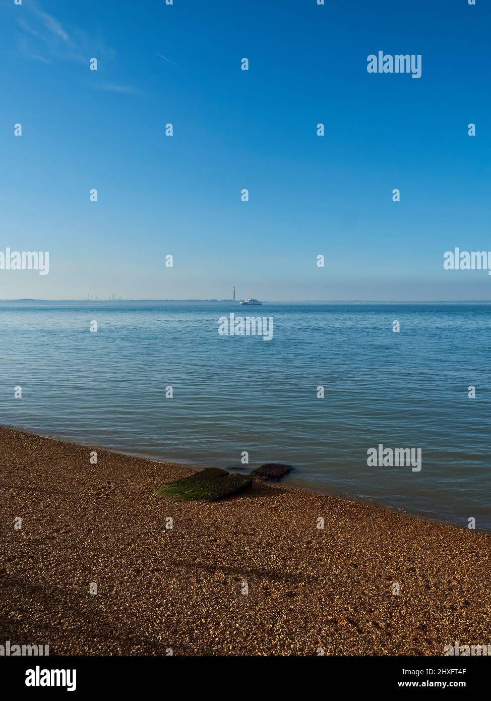 An expansive view from a shingle beach across limpid, languid seas to a ...
