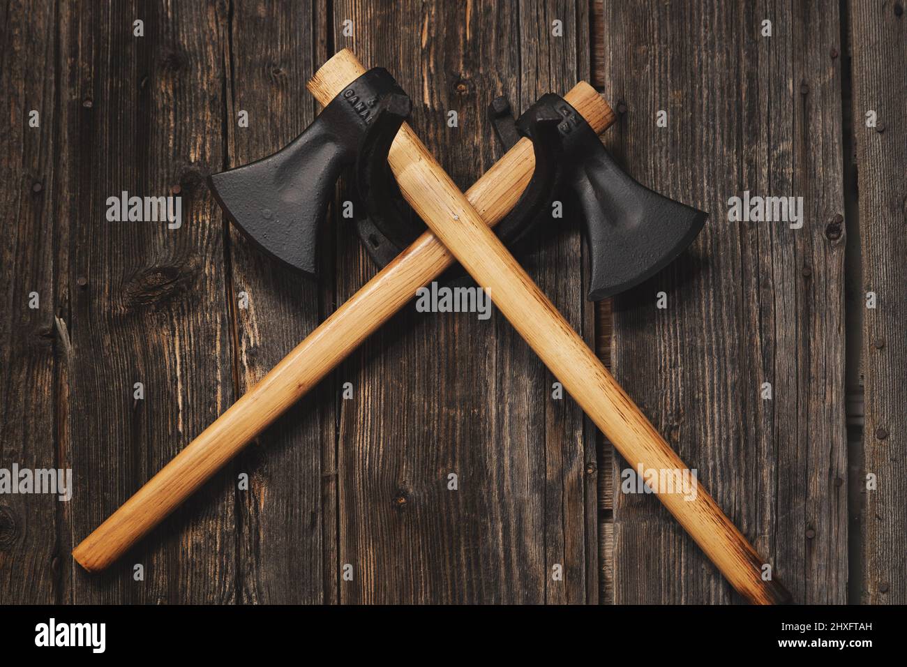 Two fireman axes crossed over each other hanging on a wood plank wall ...