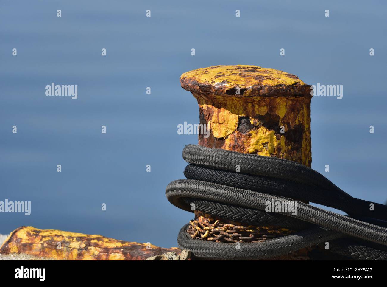 Nautical nylon double braided mooring rope on a rusty yellow bollard ...