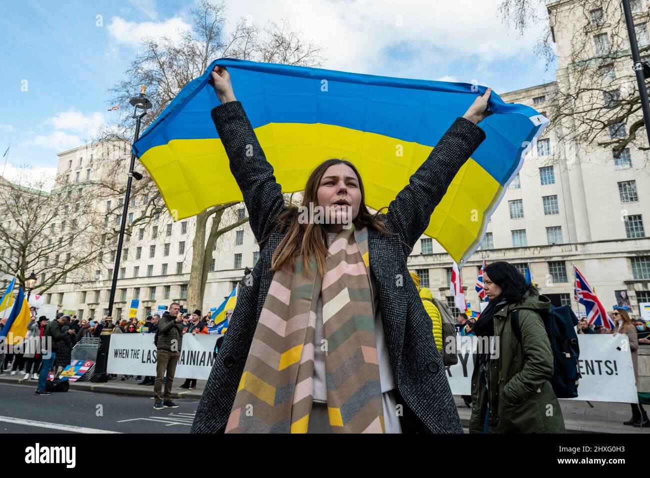 London, UK. 12 March 2022. A demonstrator holding up a Ukrainian flag ...