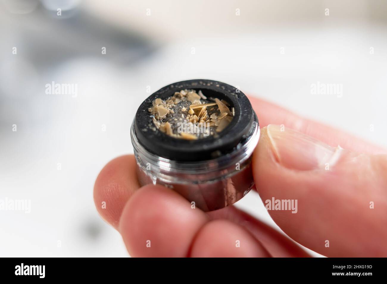 A clogged dirty faucet aerator with calcium plaque in the hand of a ...