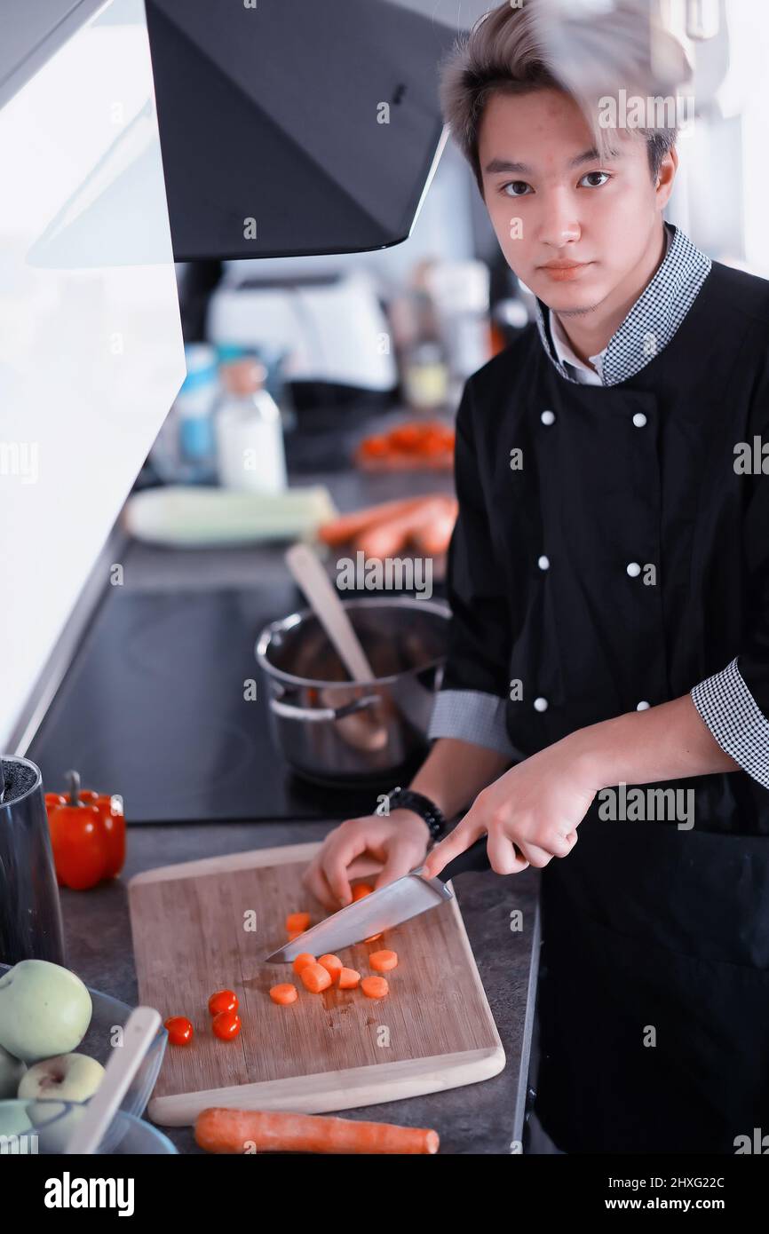 A young Asian cook in the kitchen prepares food in a cook suit Stock ...