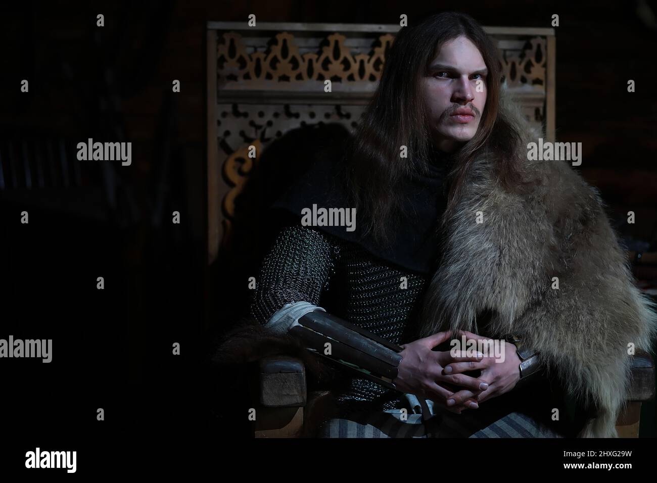 A mighty hero with long hair in chain mail armor in an ancient hall ...