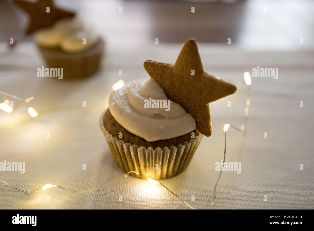 Cupcake with star cookie decorantion, twinkle lights, white tablecloth ...