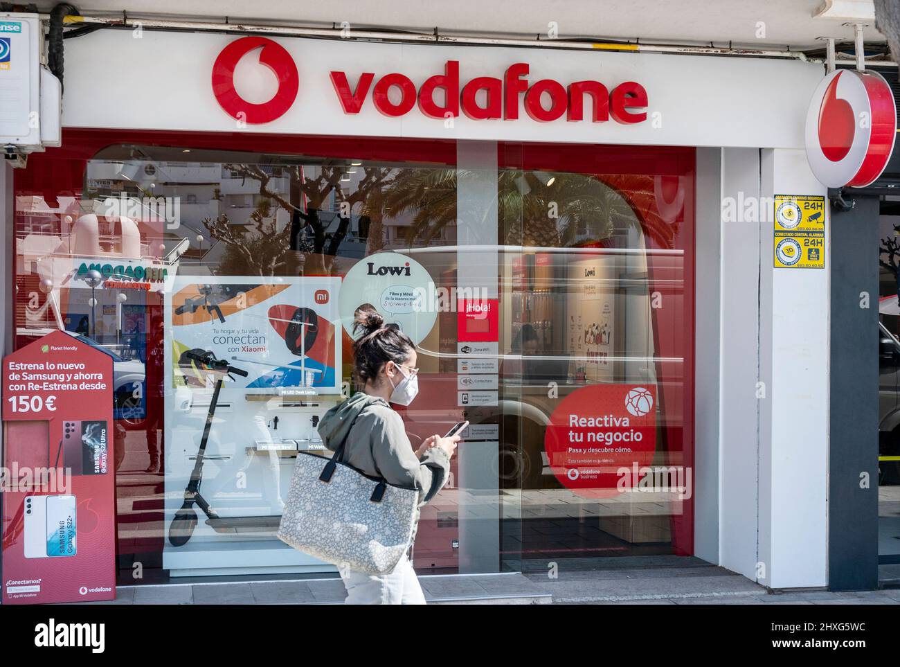 A pedestrian uses a smartphone as she walks past British multinational ...