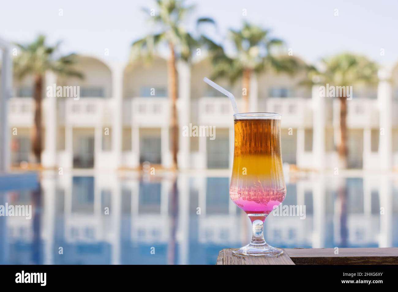 Glass of Rainbow cocktail on the pool nosing at the tropical resort ...