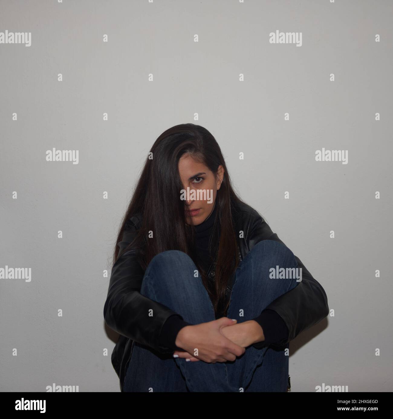 A beautiful model with her hair down hugging her legs Stock Photo - Alamy