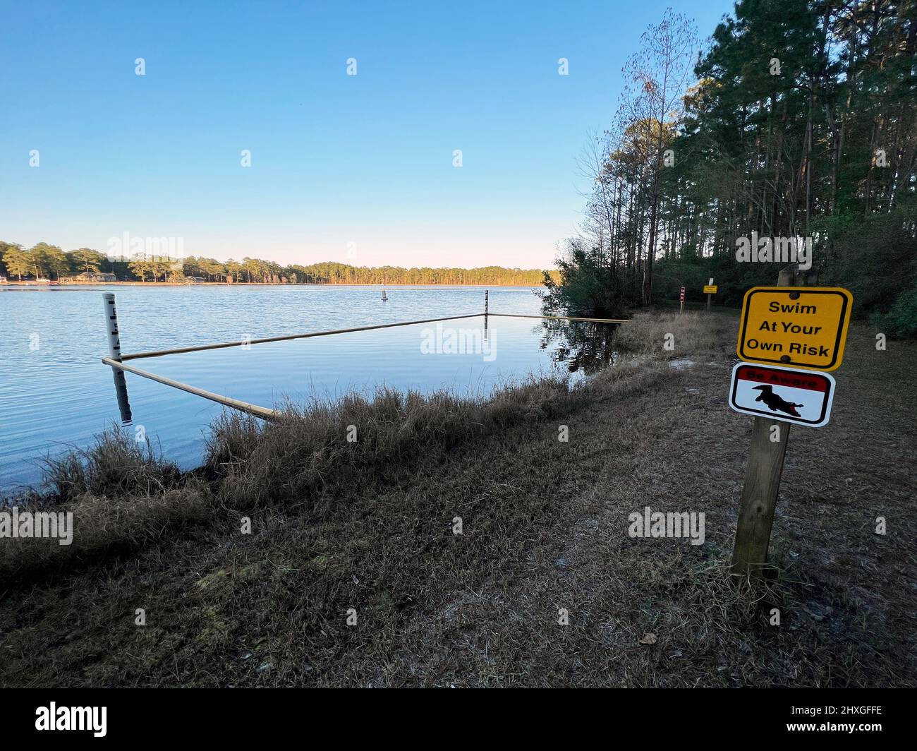 Due to the presence of alligators, a swim at your own risk sign is ...
