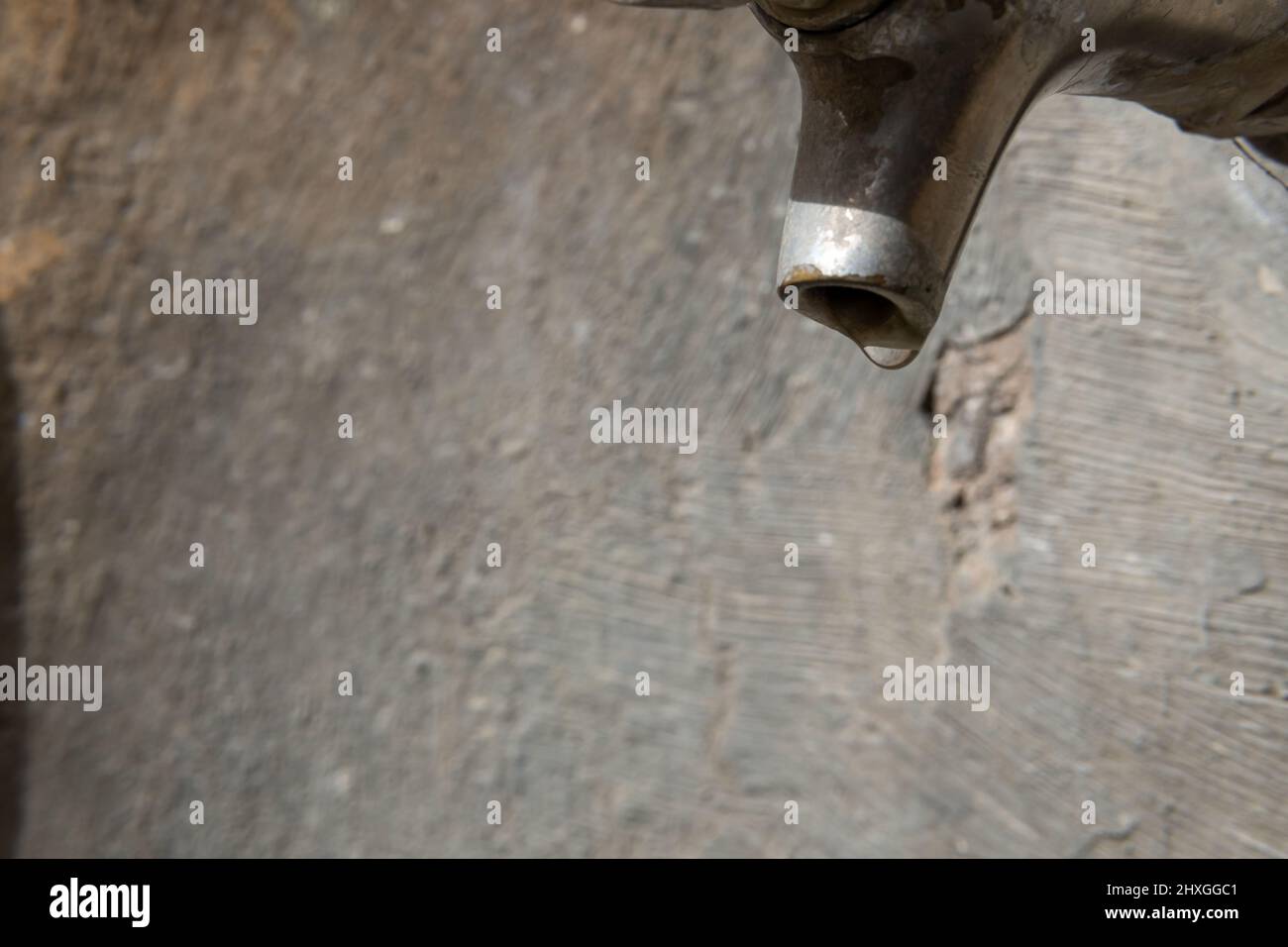 Close-up of a metal faucet with a drop of water. Conceptual image of ...