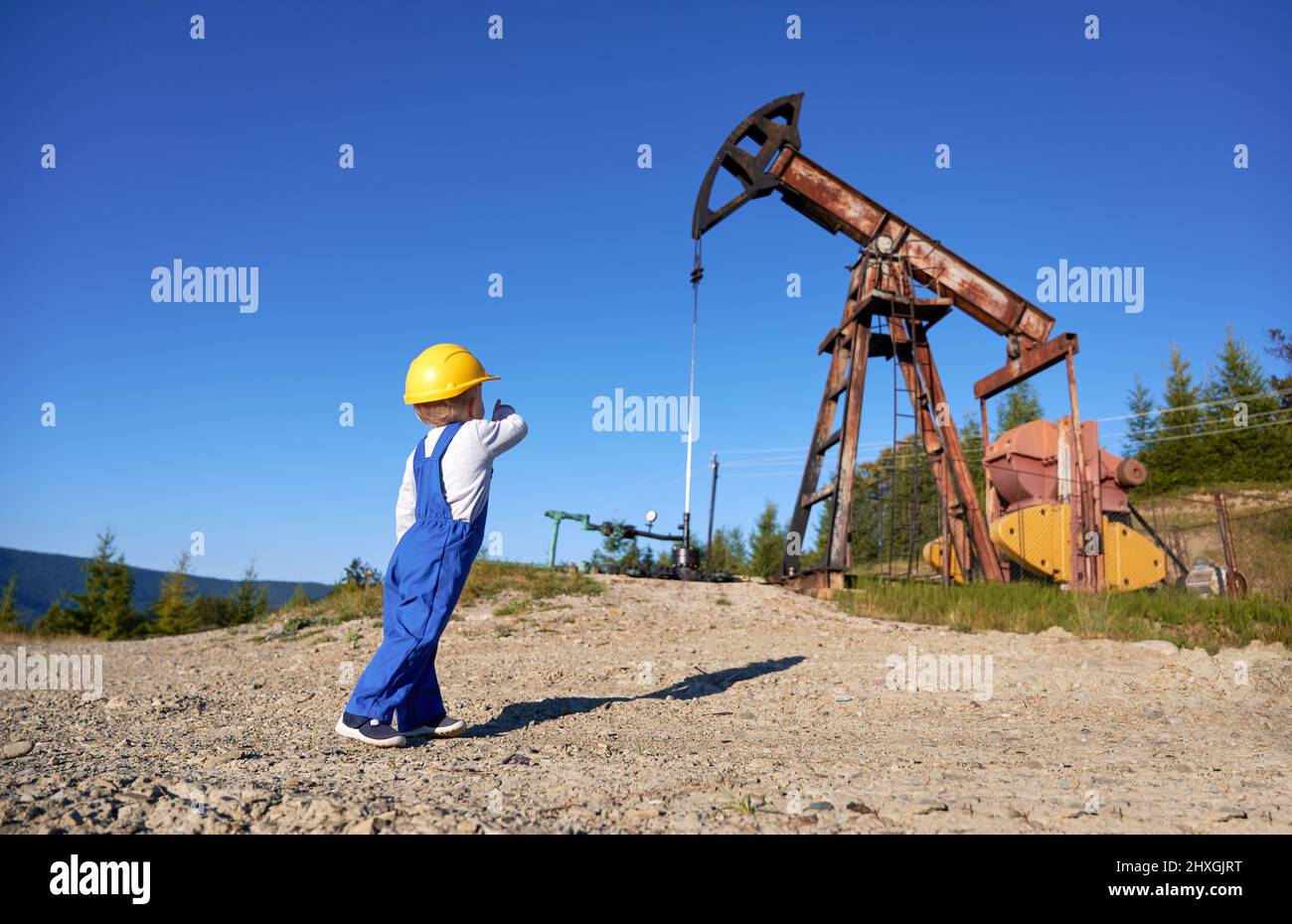 Back view of little boy in construction helmet who standing nearby ...