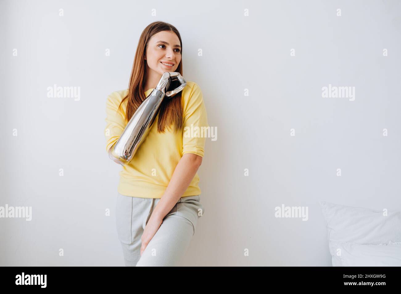 Pretty smiling blonde young woman with elegant bionic prosthesis arm ...