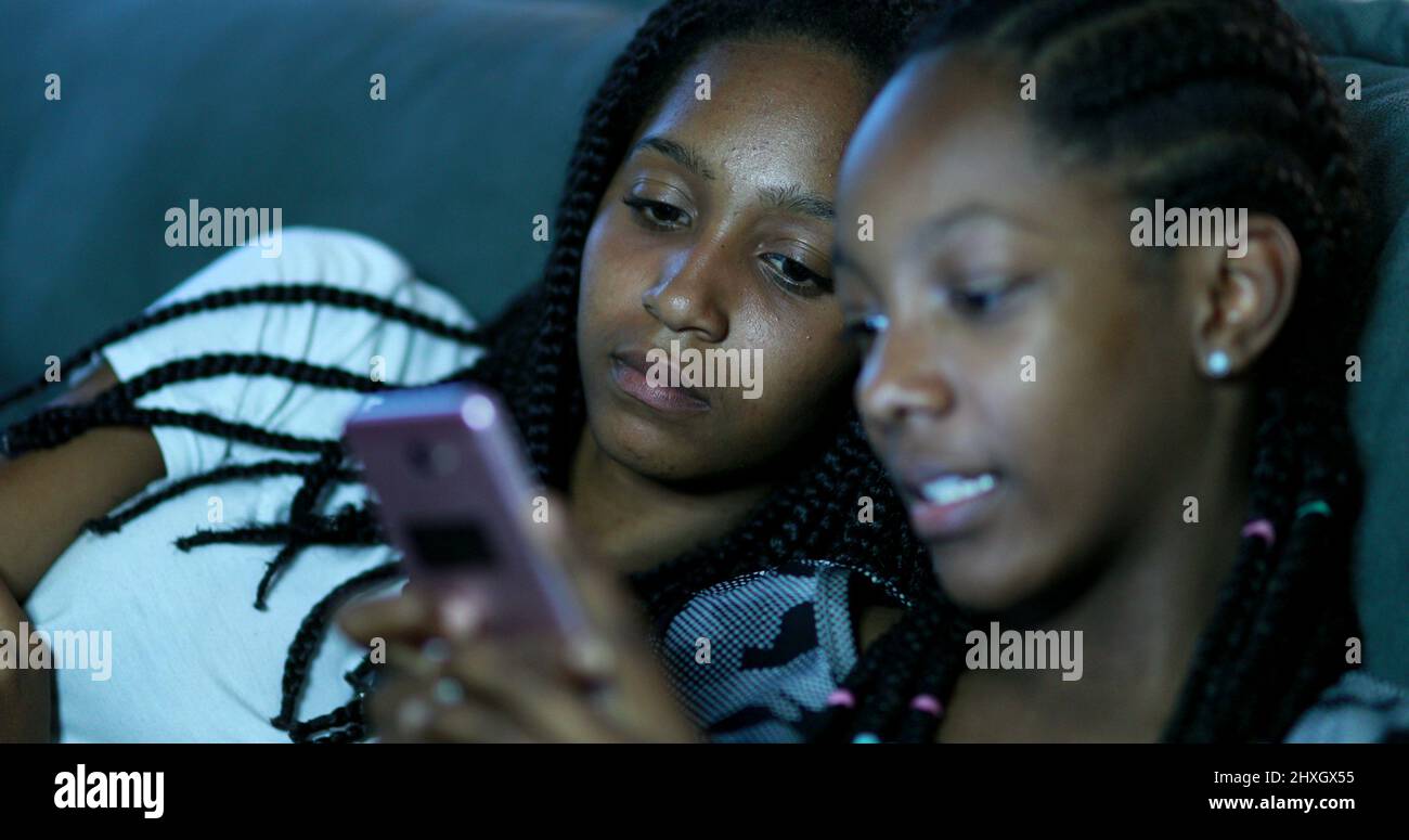 Candid black girls looking at cellphone screen. African American sisters using technology at ...