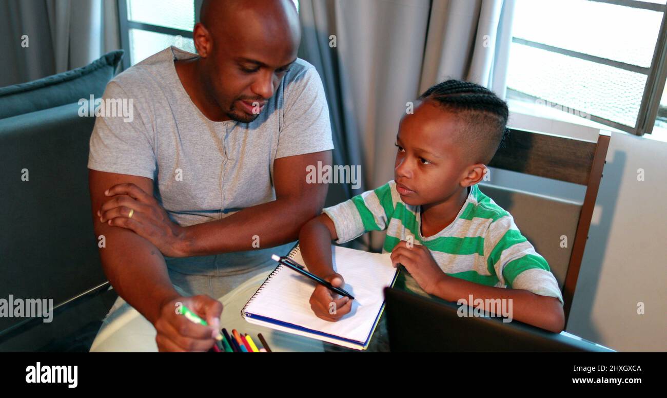 Father helping son with homework at home. African black dad mentoring ...