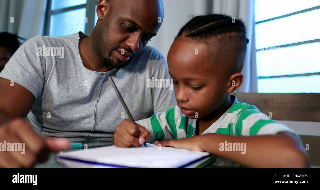 Father helping son with homework at home. African black dad mentoring ...