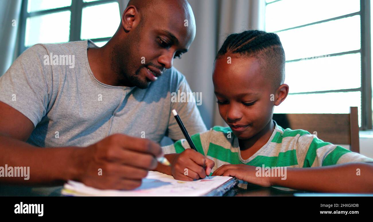 Father helping son with homework at home. African black dad mentoring ...