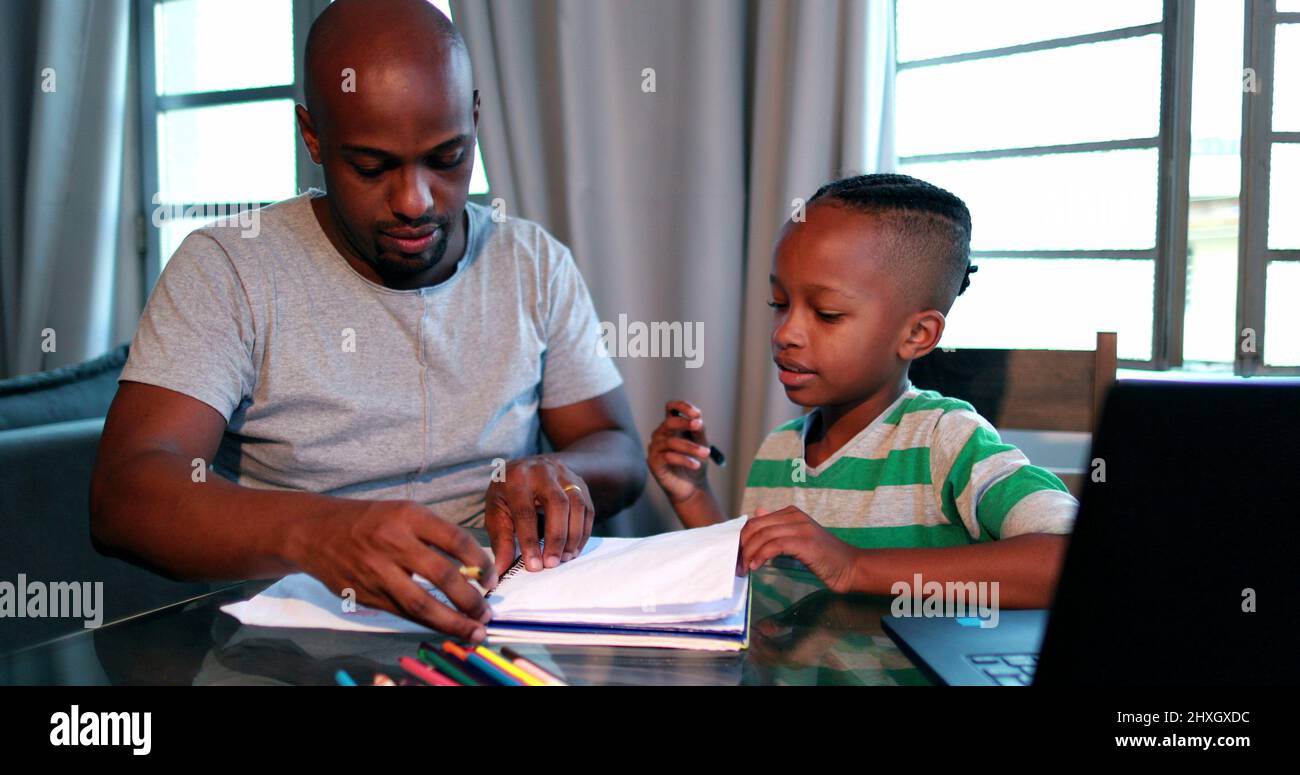 Father helping son with homework at home. African black dad mentoring ...