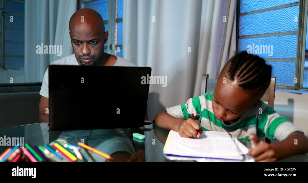 Father multi-tasking using computer laptop at home. Candid authentic ...
