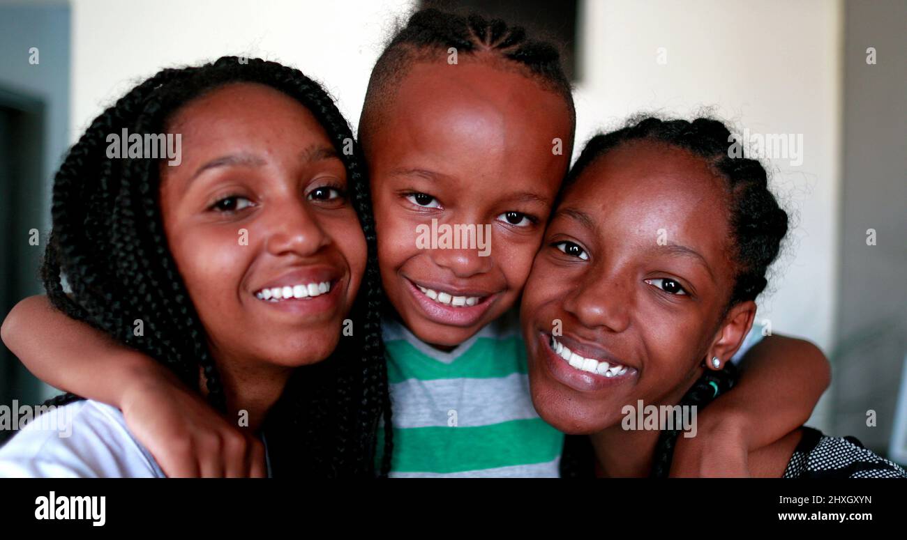 Little brother embracing teen sisters. African mixed race black ...