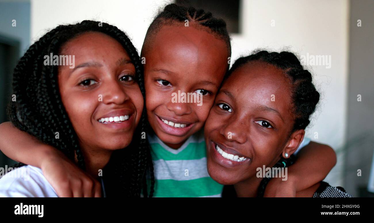 Little brother embracing teen sisters. African mixed race black ...