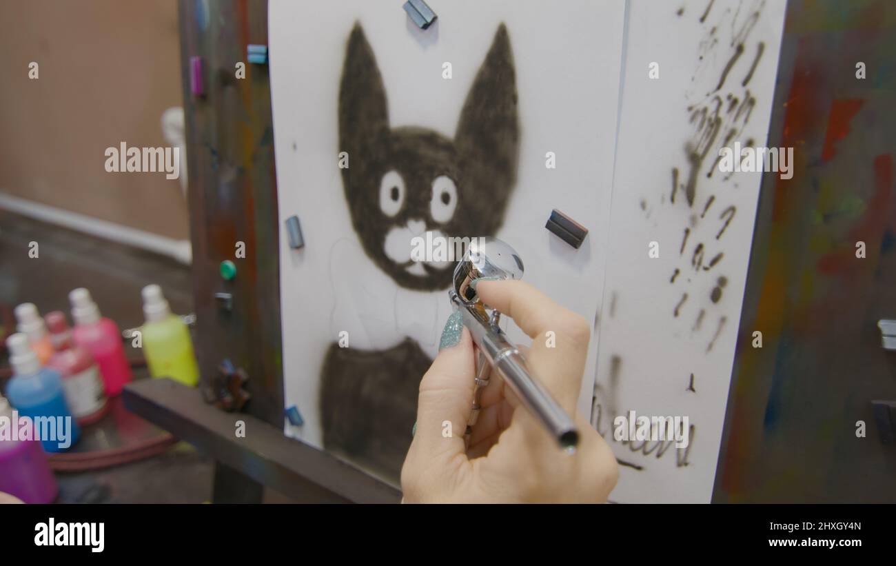 Woman artist learns to paint with airbrush with acrylic dye, paper and ...