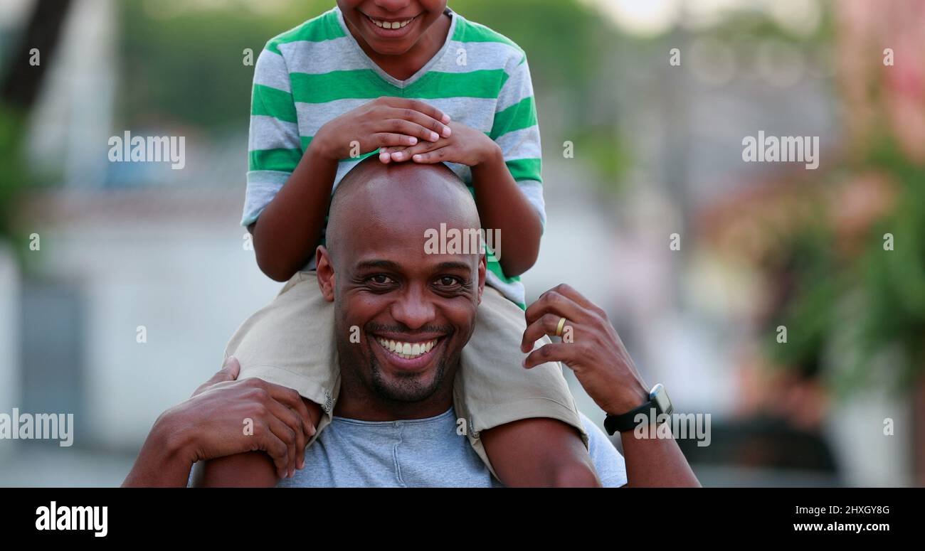 Son on father shoulders. Happy African child and dad bonding together ...