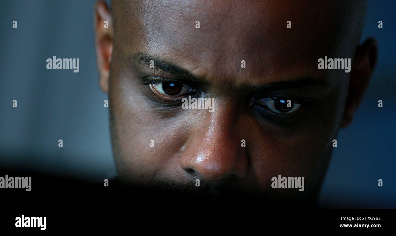 Tired black man working late at night in front of computer. Close-up ...