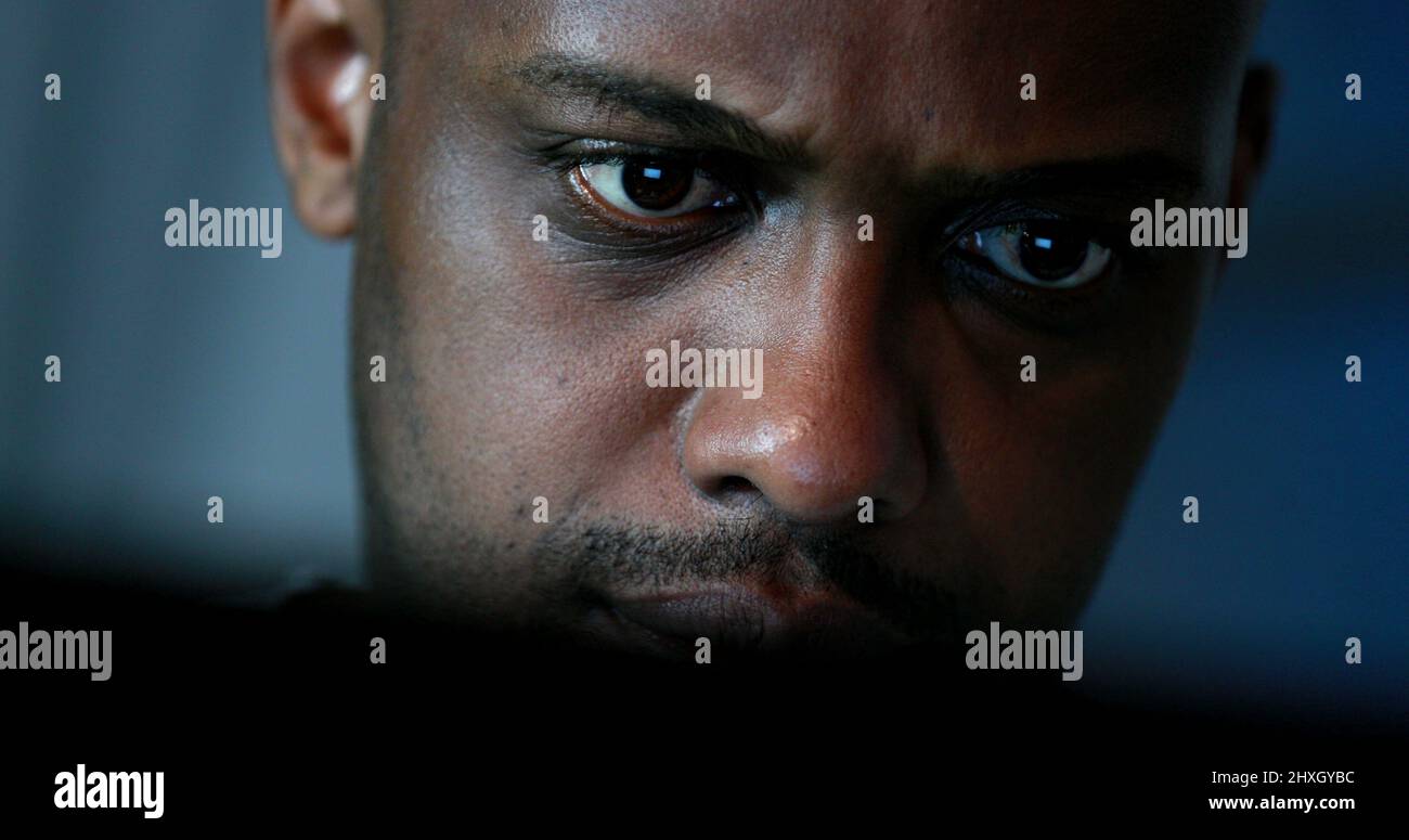 Tired black man working late at night in front of computer. Close-up ...