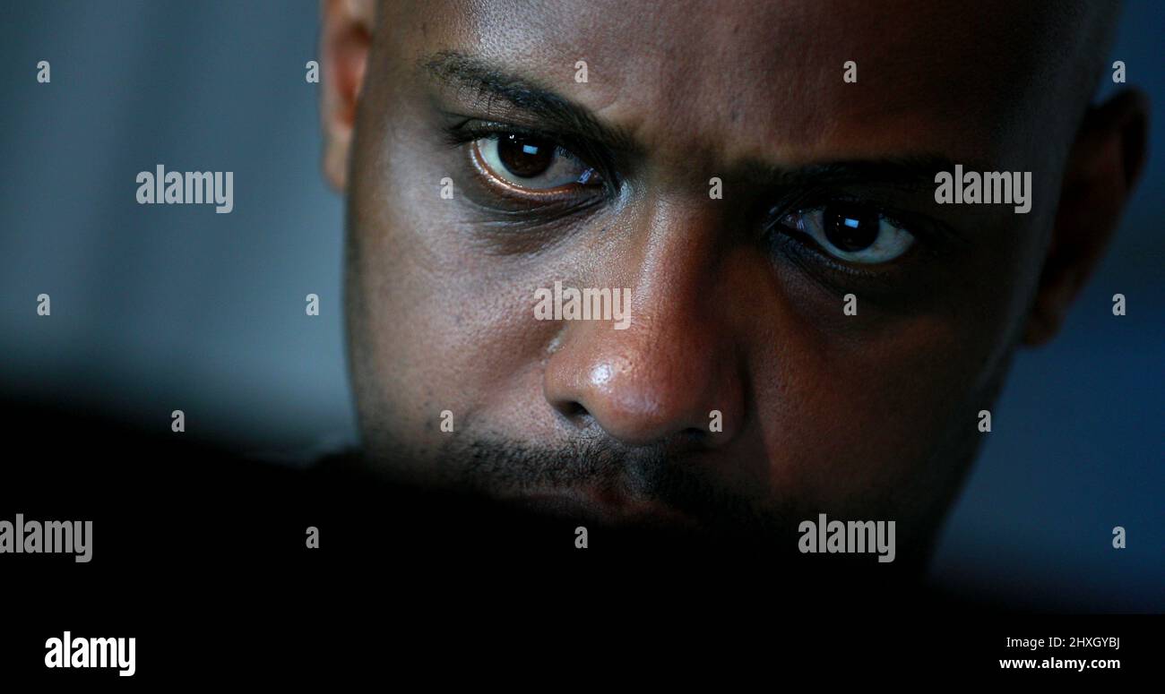 Tired black man working late at night in front of computer. Close-up ...