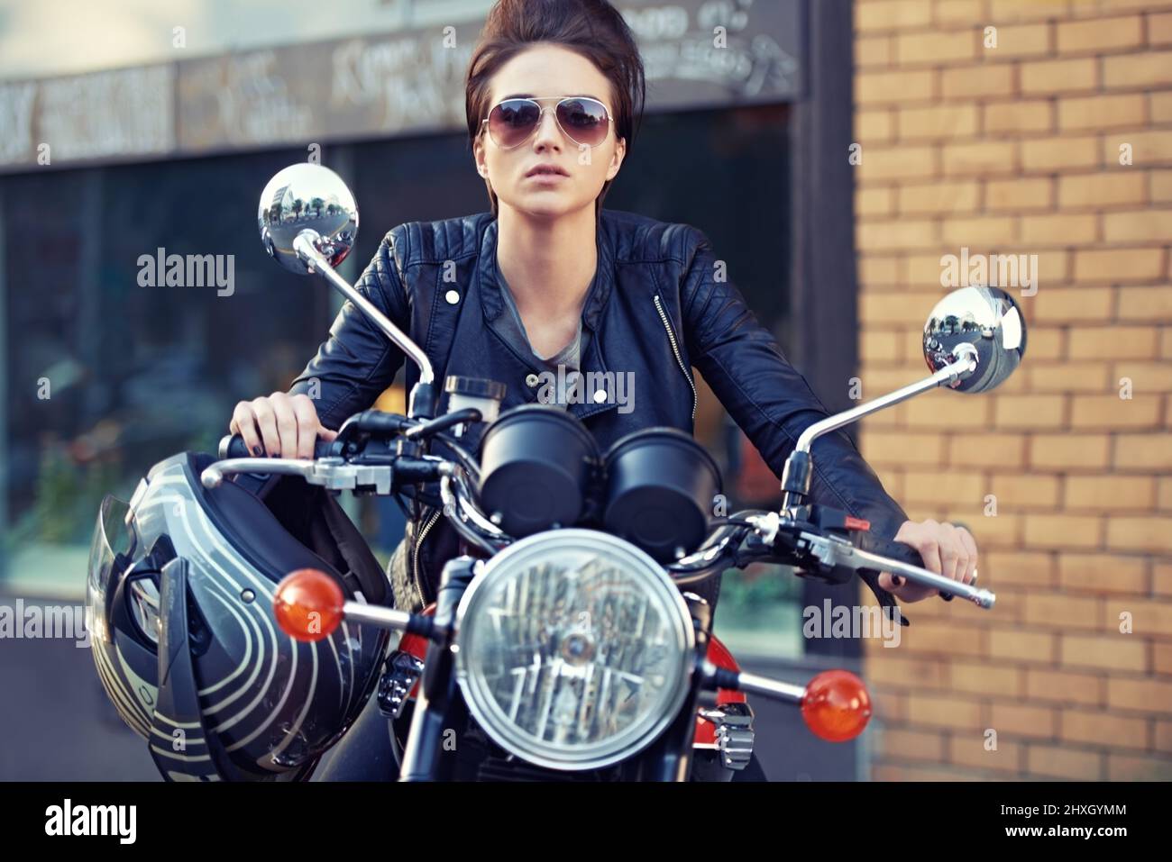 Motorcycle style. Shot of a young and stylish female motorcycle rider ...