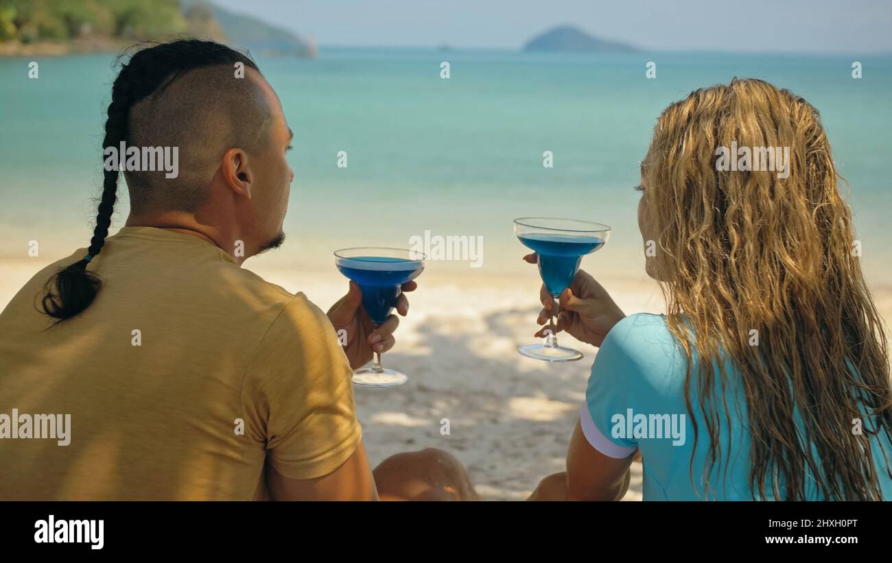 The love couple is holding a glass of blue curacao cocktail, on sea ...